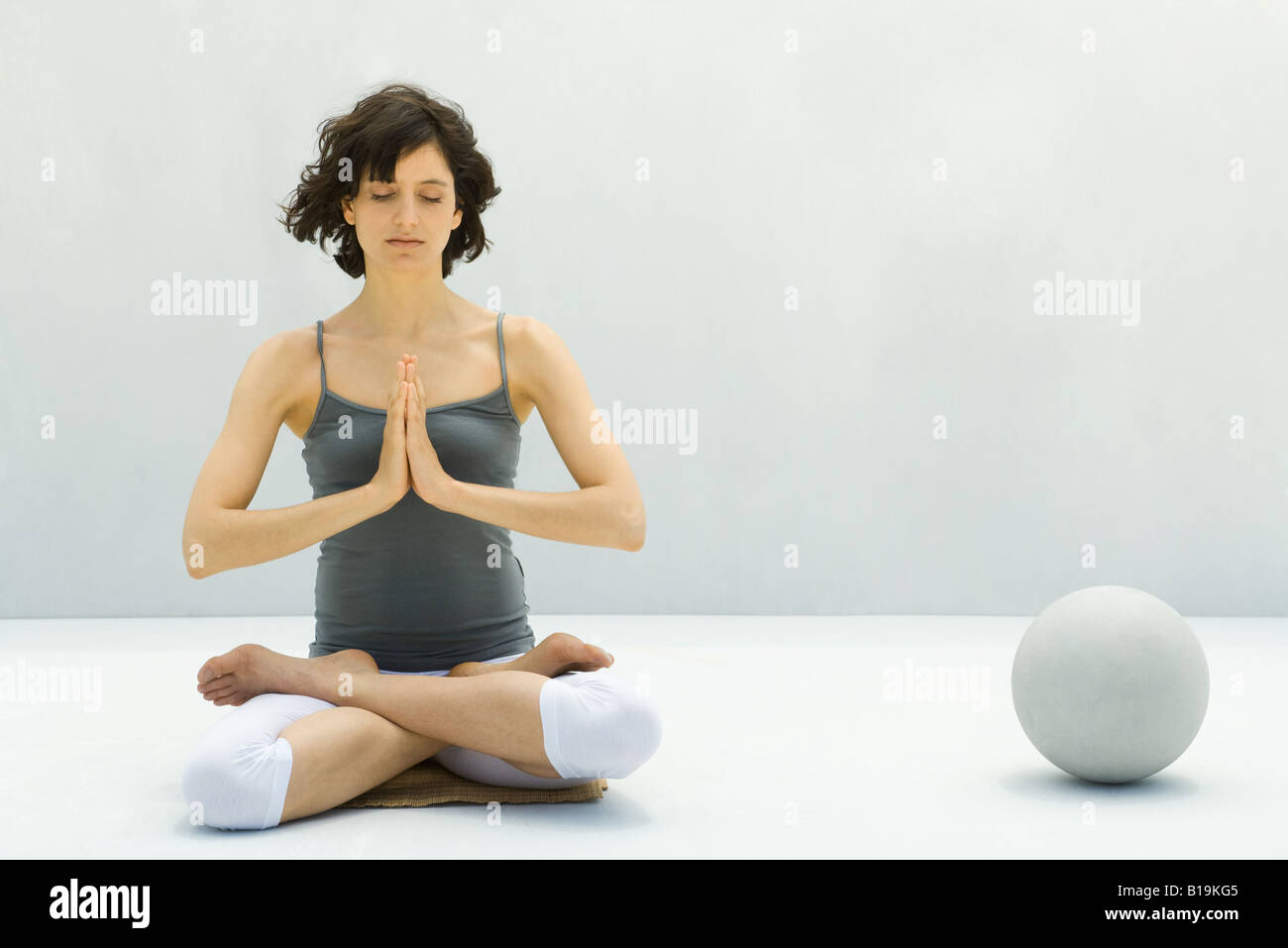 Woman sitting in lotus position beside ball, eyes closed Stock Photo ...