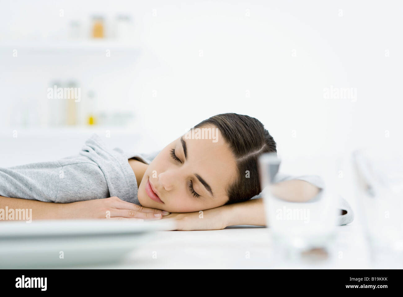 Female at kitchen table, head resting on arms, eyes closed Stock Photo ...