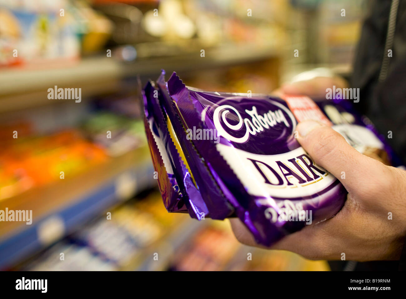 Dairy Milk Cadbury chocolate bars are stacked by a store employee in a ...