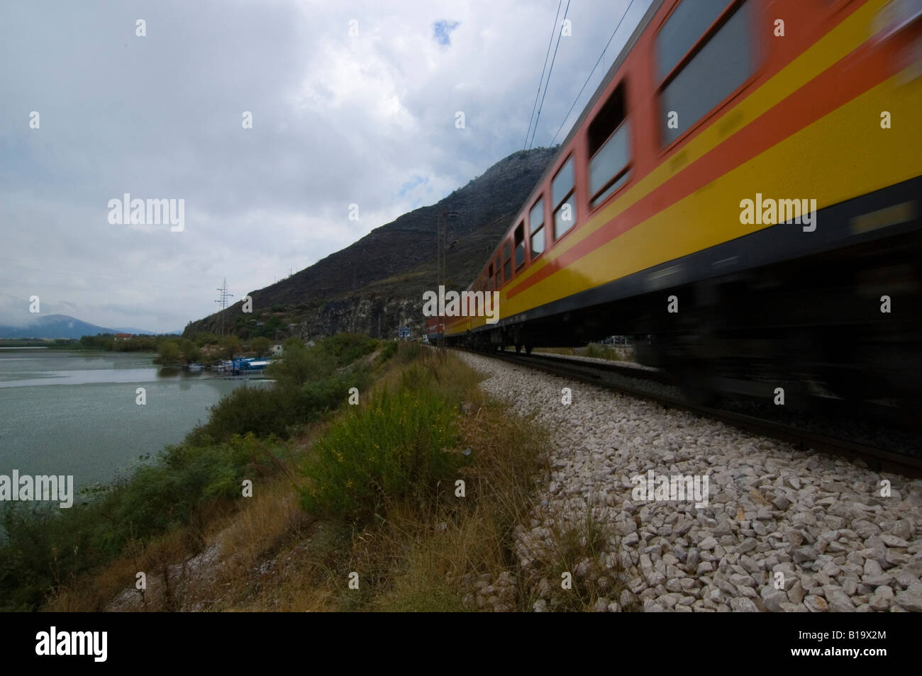 Red yellow train sweeps away next to the Unesco protected Skadar lake ...