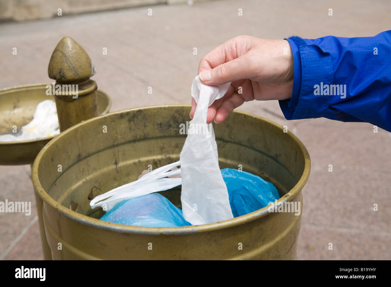 Europe Person dropping a wet wipe tissue into a litter bin outside ...