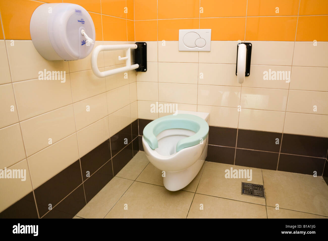 Public disabled toilet inside clean tiled cubicle with drop down ...