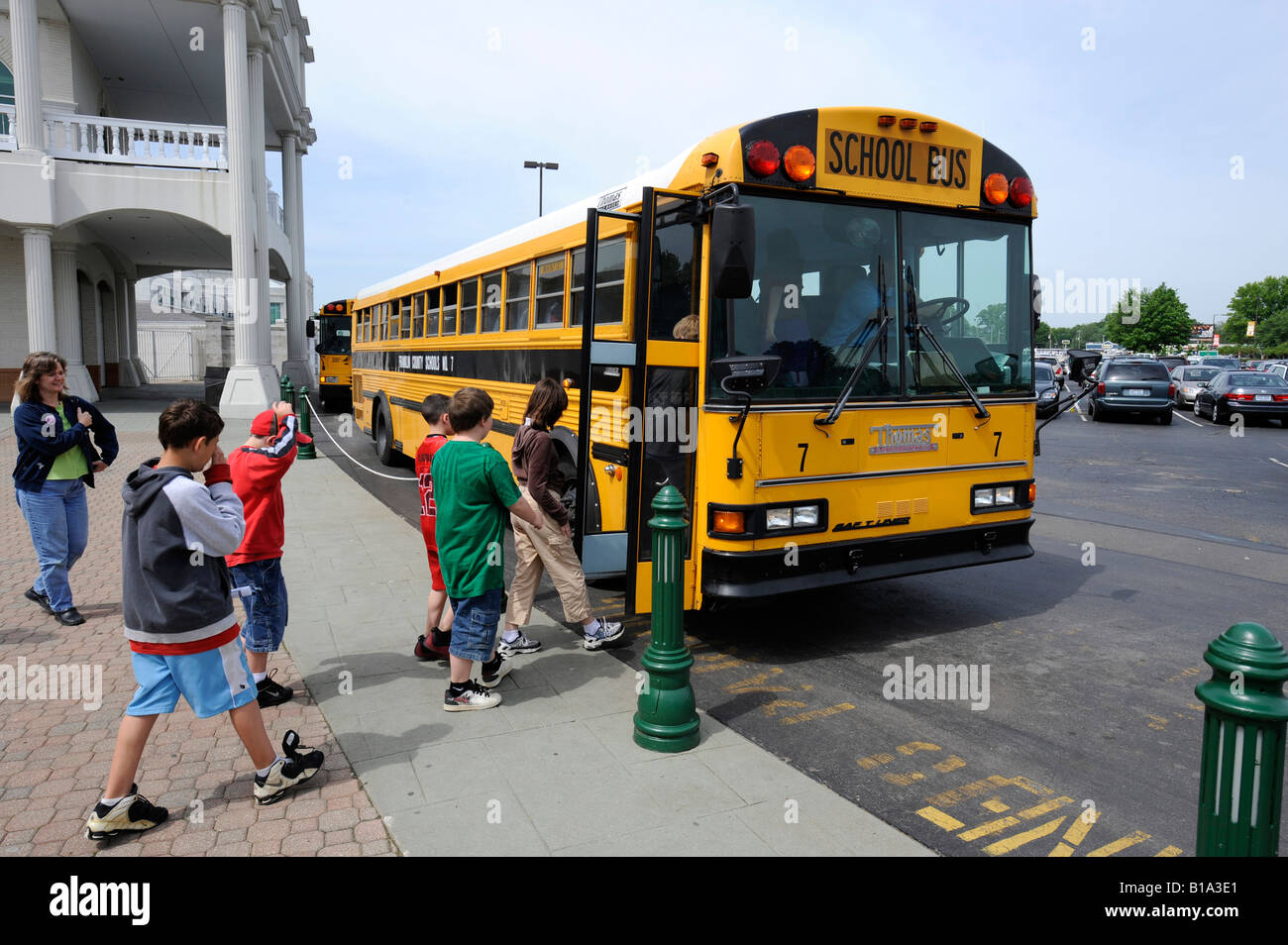 Elementary school age children board a yellow school bus after a field ...