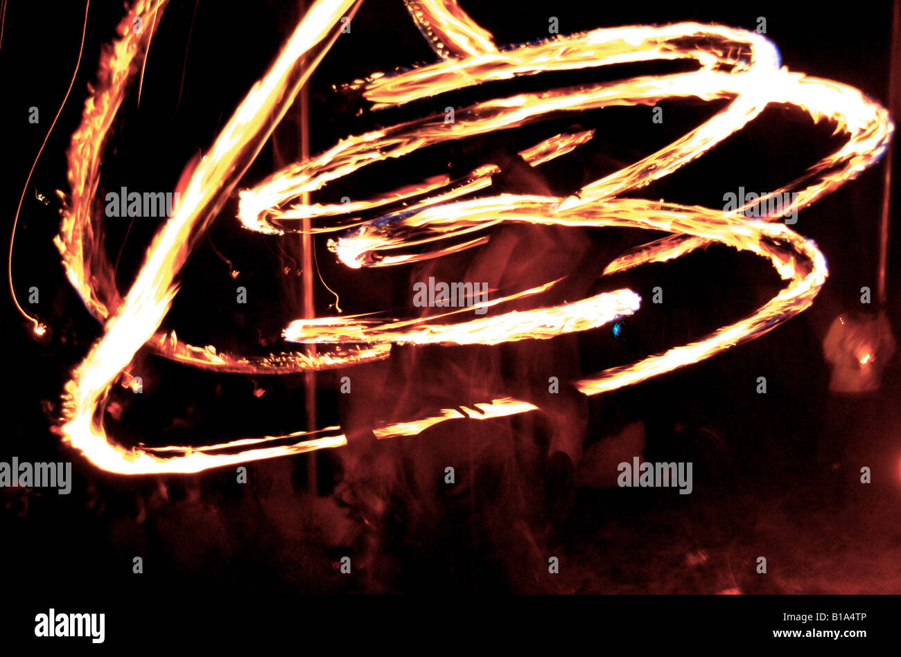 A festival-goer using Fire-Poy at night in the fields of Glastonbury ...