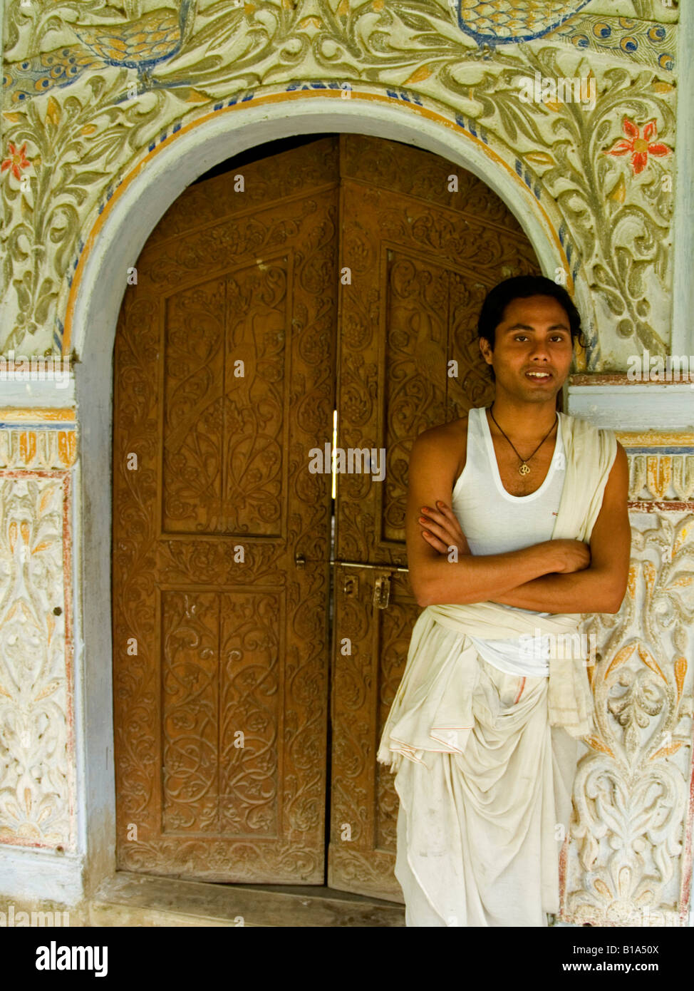 Vishnavaite monk standing in wooden monastery doorway on Majuli Island ...