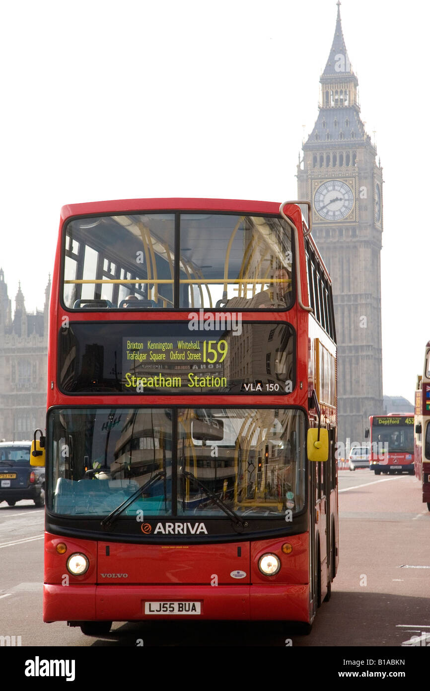 A red London bus crosses London Bridge. The Palace of Westminster can ...