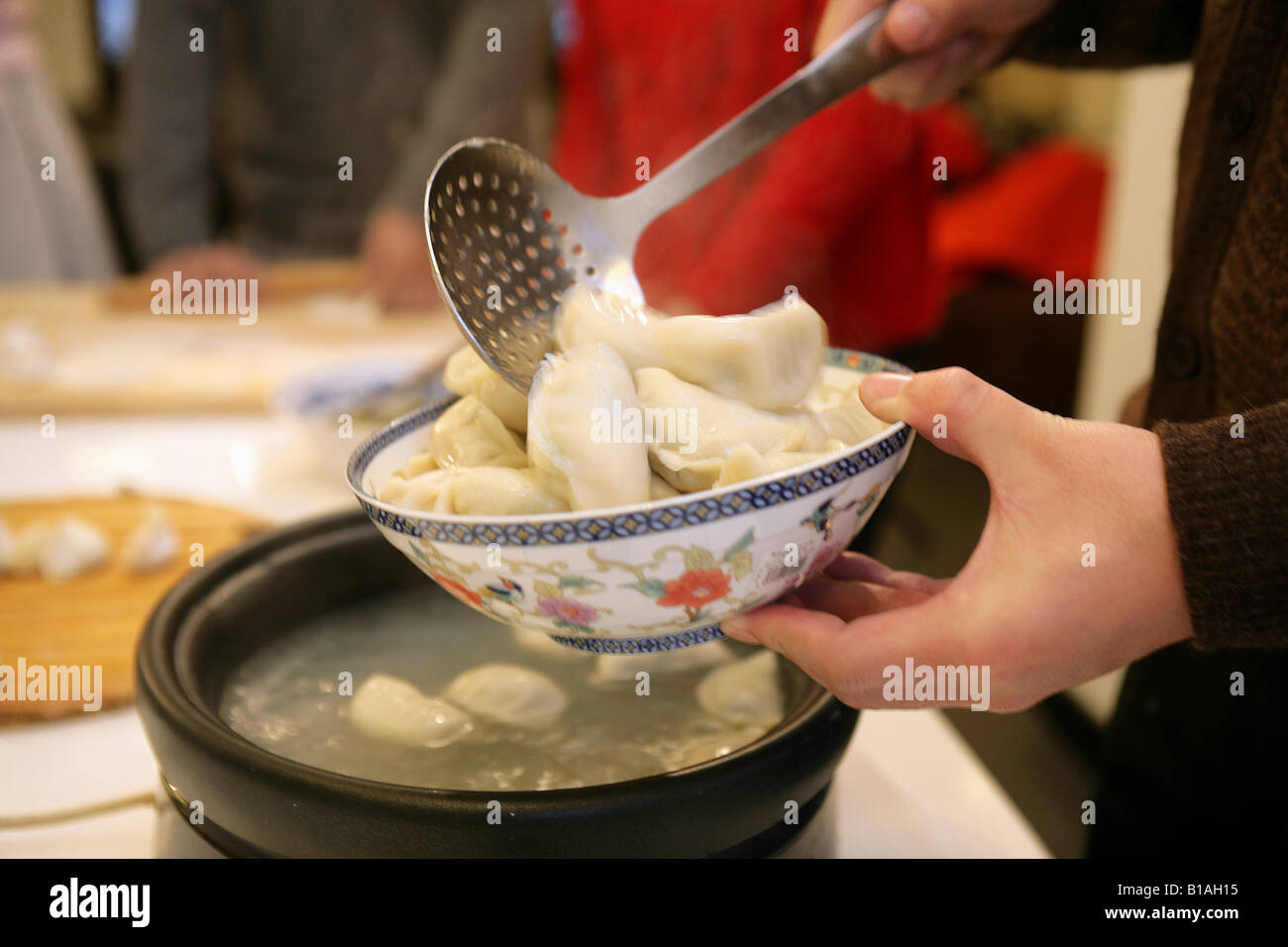 Chinese man filling Chinese dumplings in a bowl on New Year's Eve Stock ...