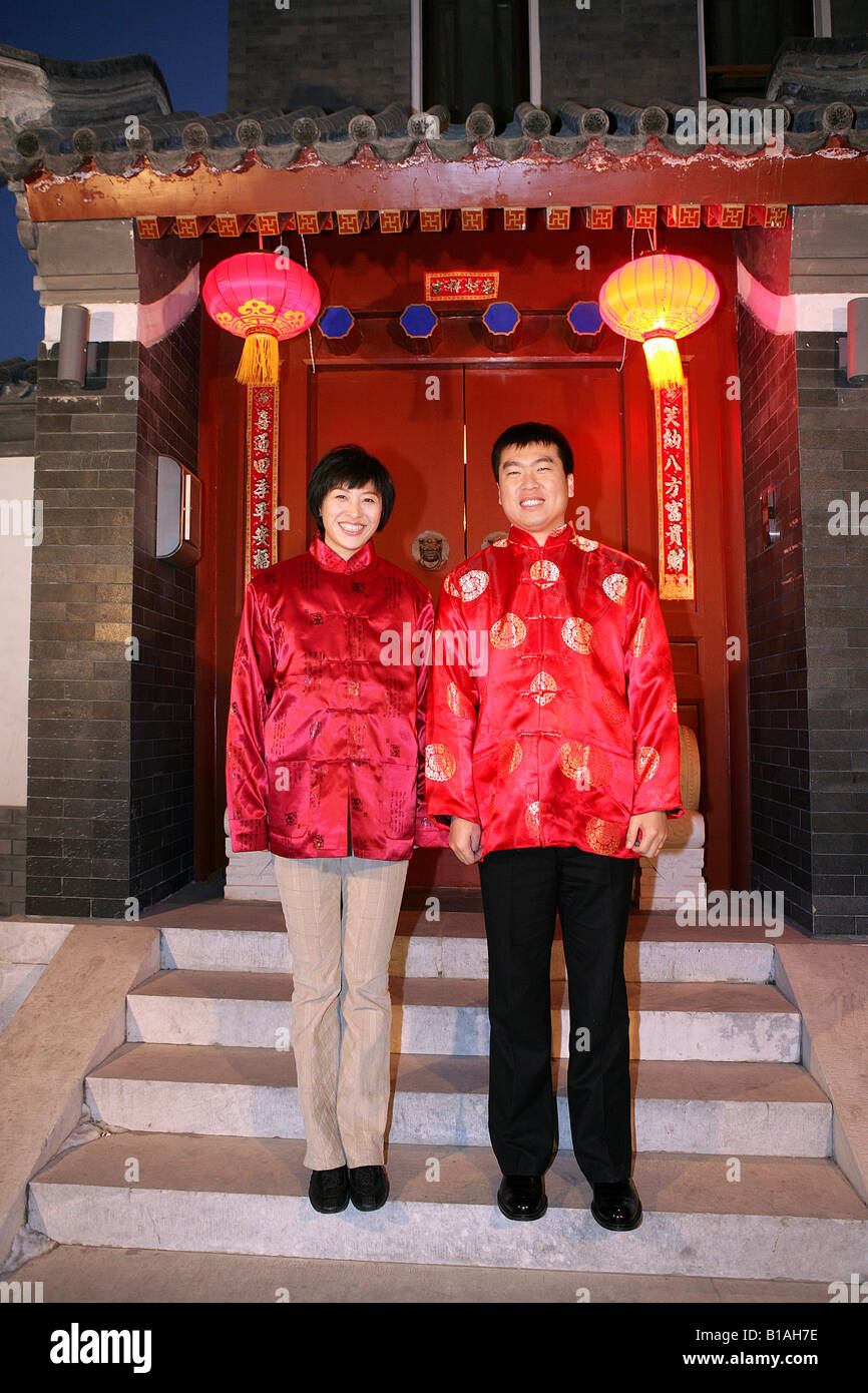 Chinese young couple gesturing welcome at the gate celebrating Chinese ...