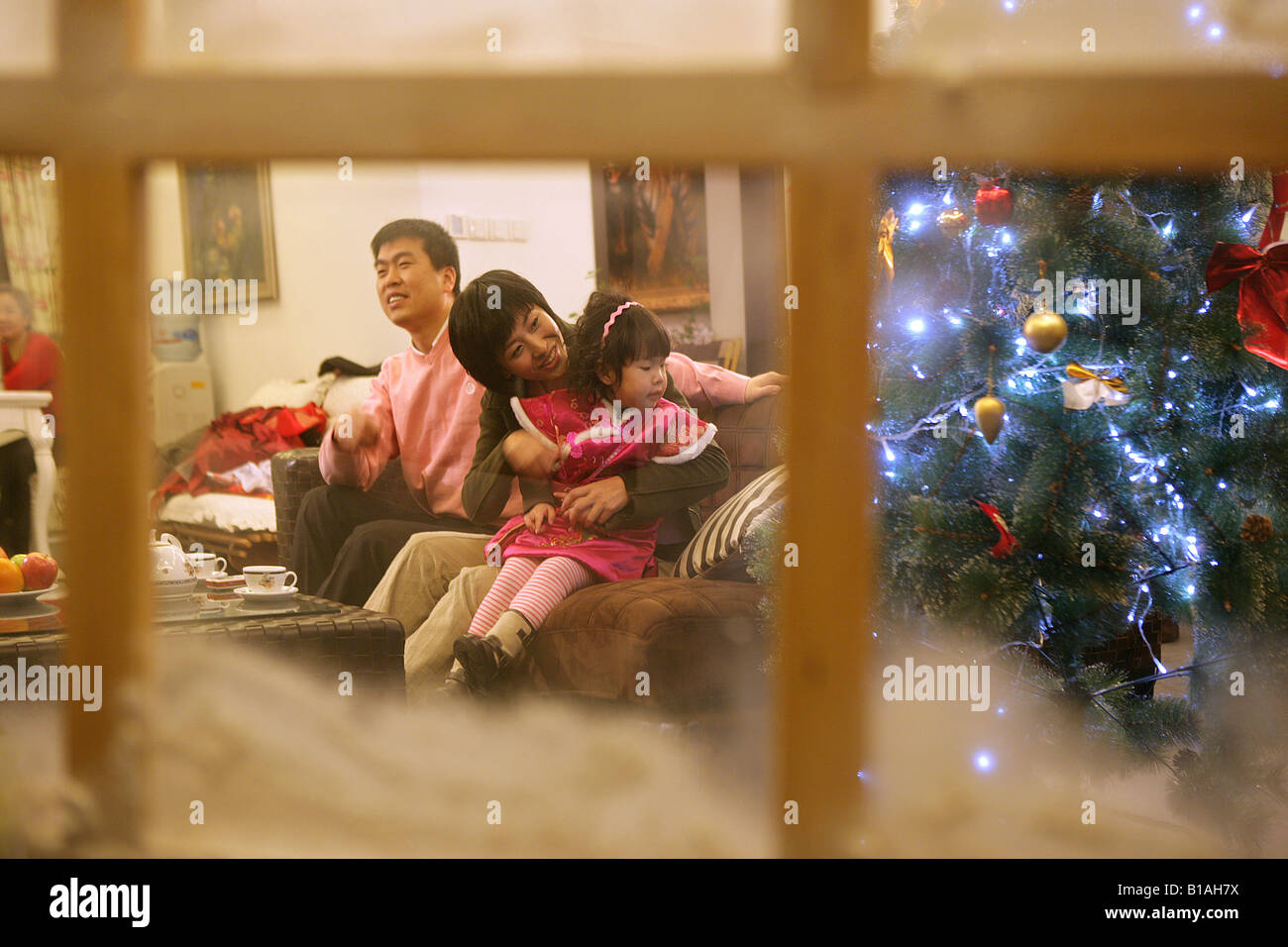 Chinese young couple watching TV with their child Stock Photo - Alamy