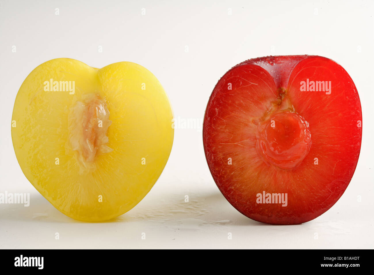 A red plum and a yellow plum cut in half Stock Photo - Alamy