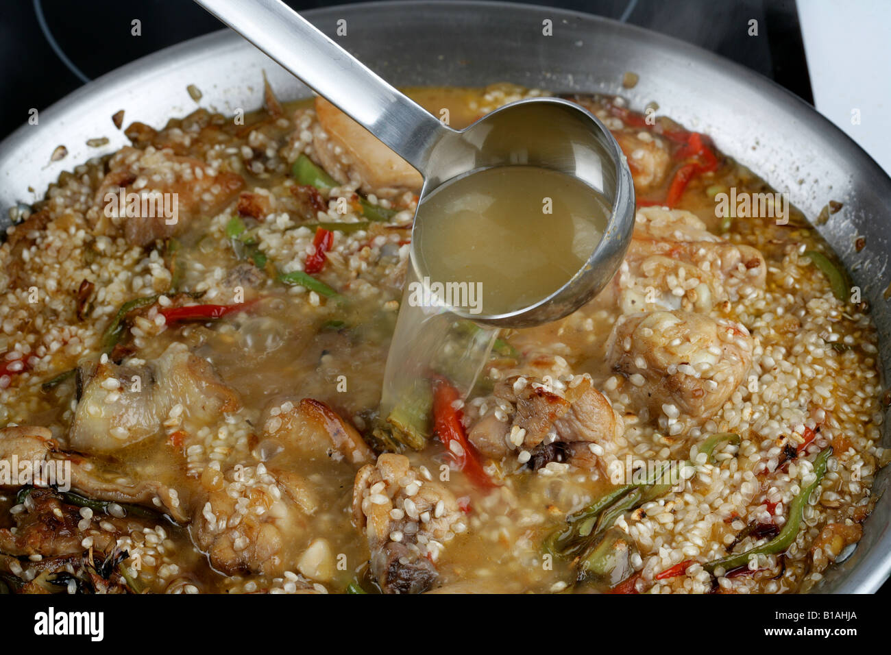 Adding stock to paella pan Stock Photo - Alamy