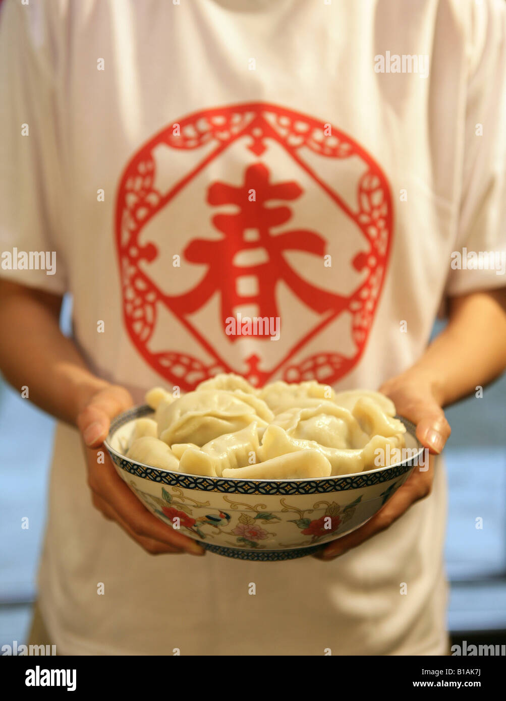 Chinese young woman holding a bowl of Chinese dumpling Stock Photo - Alamy