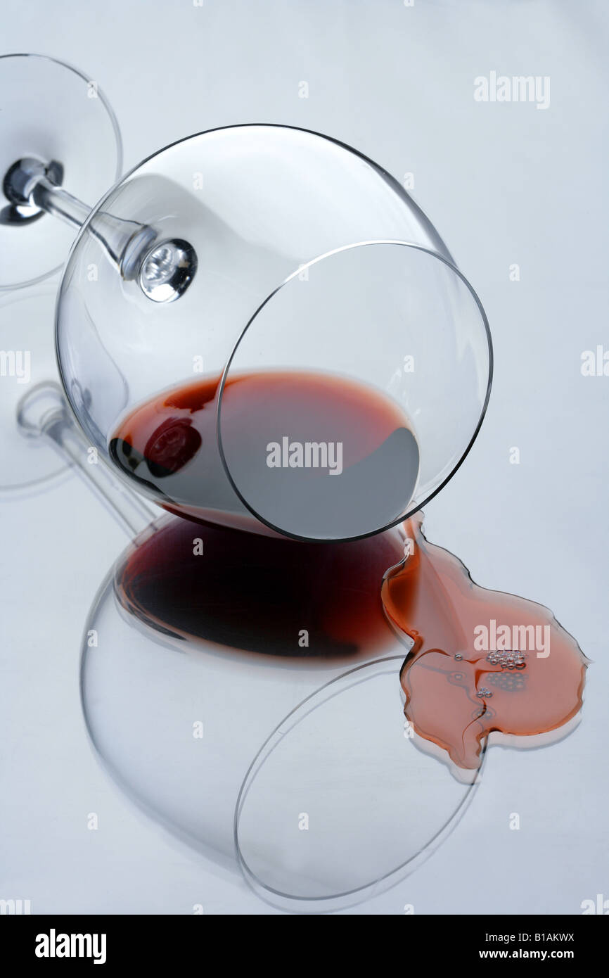 Wine glass with some wine spilt over the table Stock Photo - Alamy