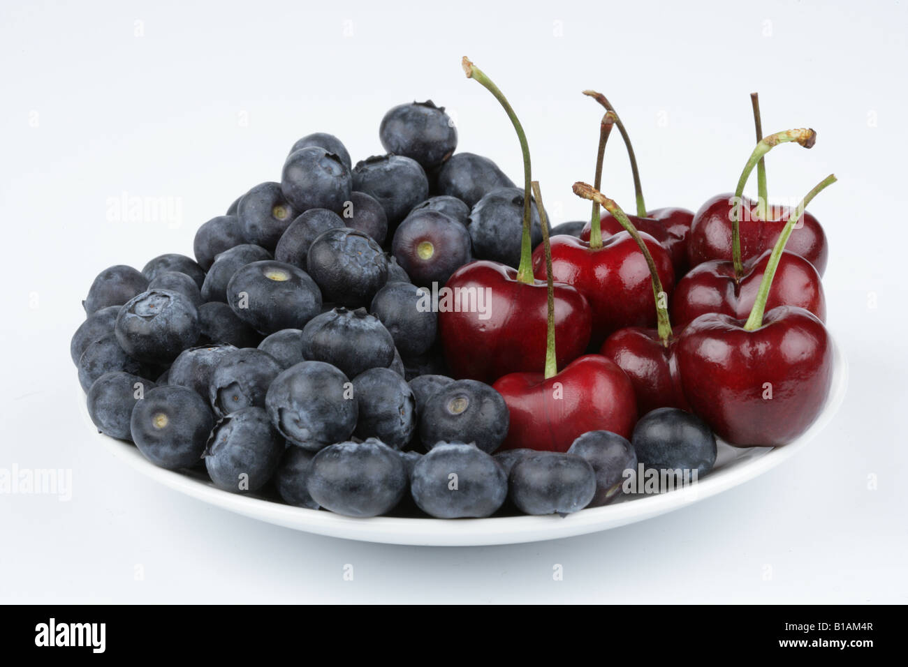 Blueberries and cherries on white background Stock Photo - Alamy