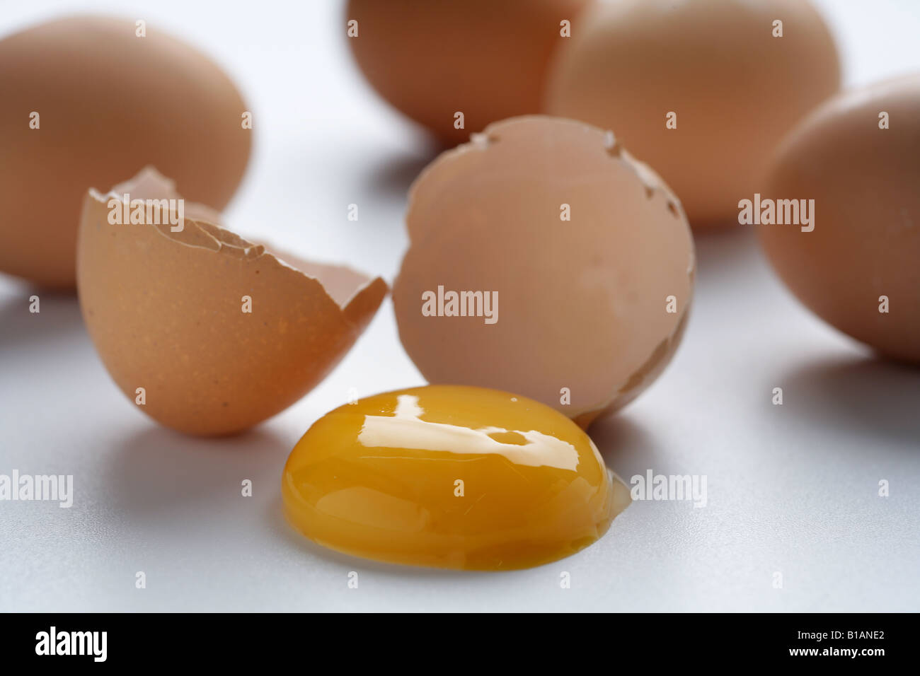 One broken egg with the yolk spilling, more eggs in the background ...