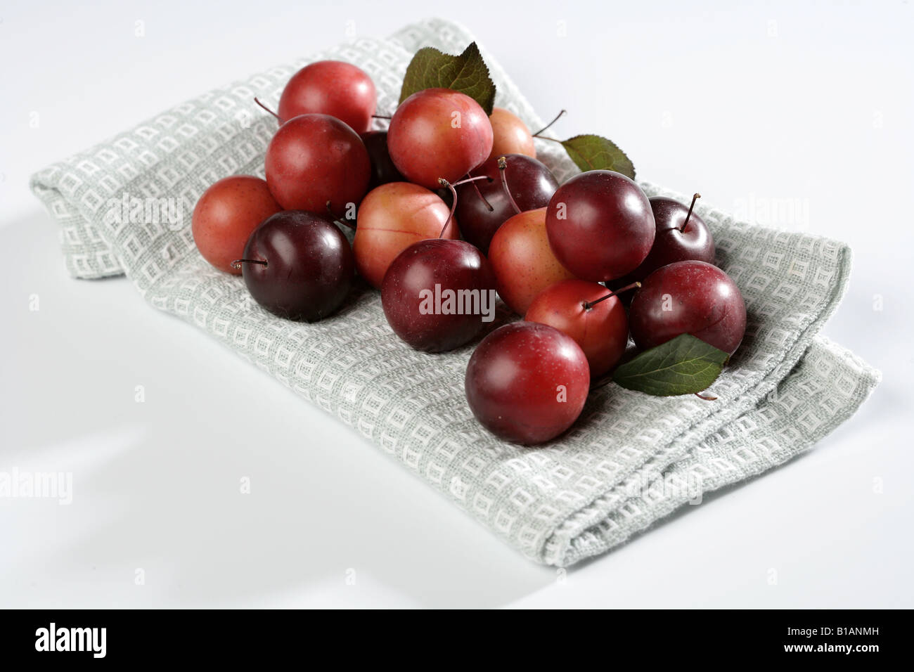 Plums on a cloth and white background Stock Photo - Alamy