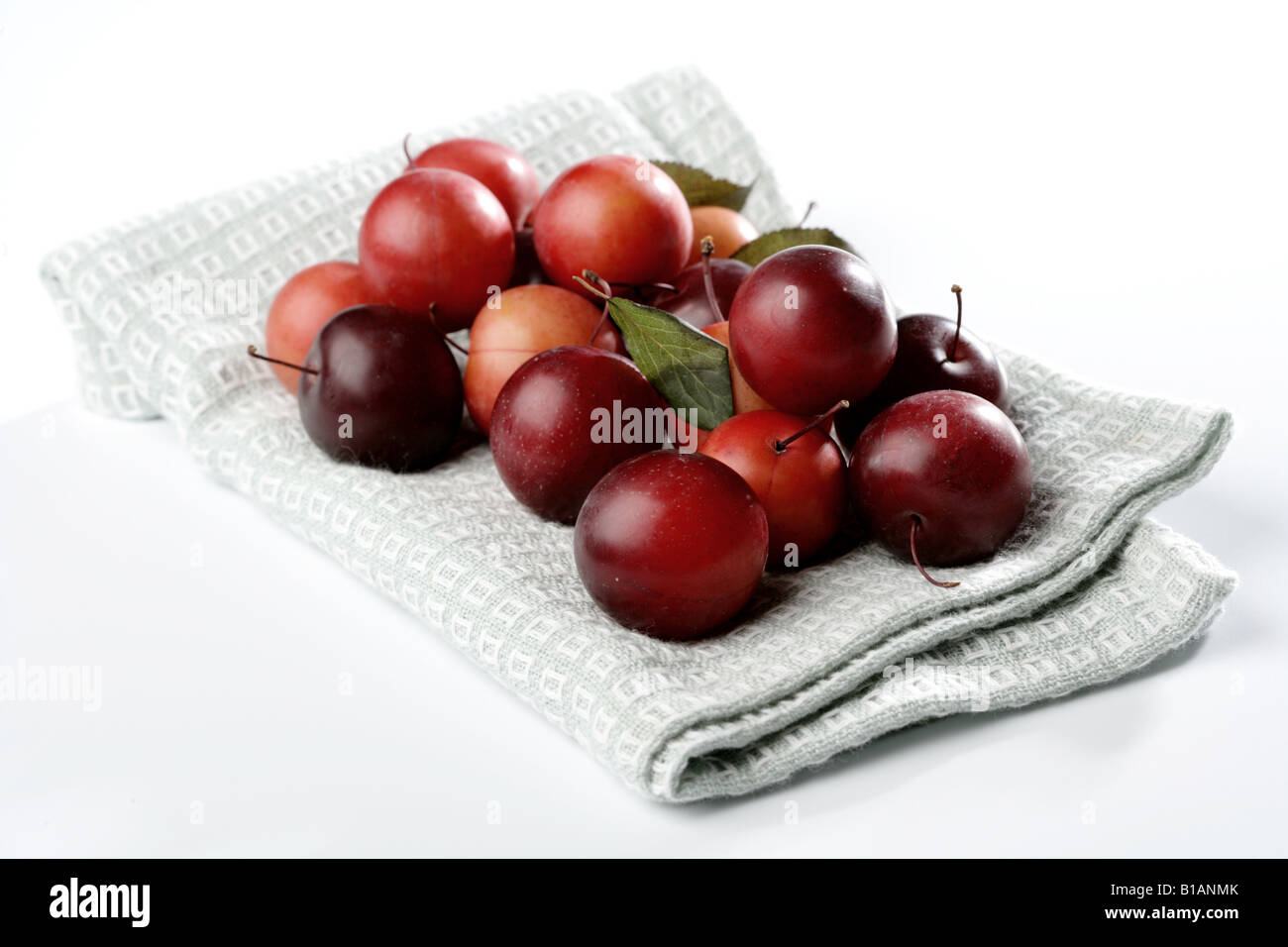 Plums on a cloth and white background Stock Photo - Alamy
