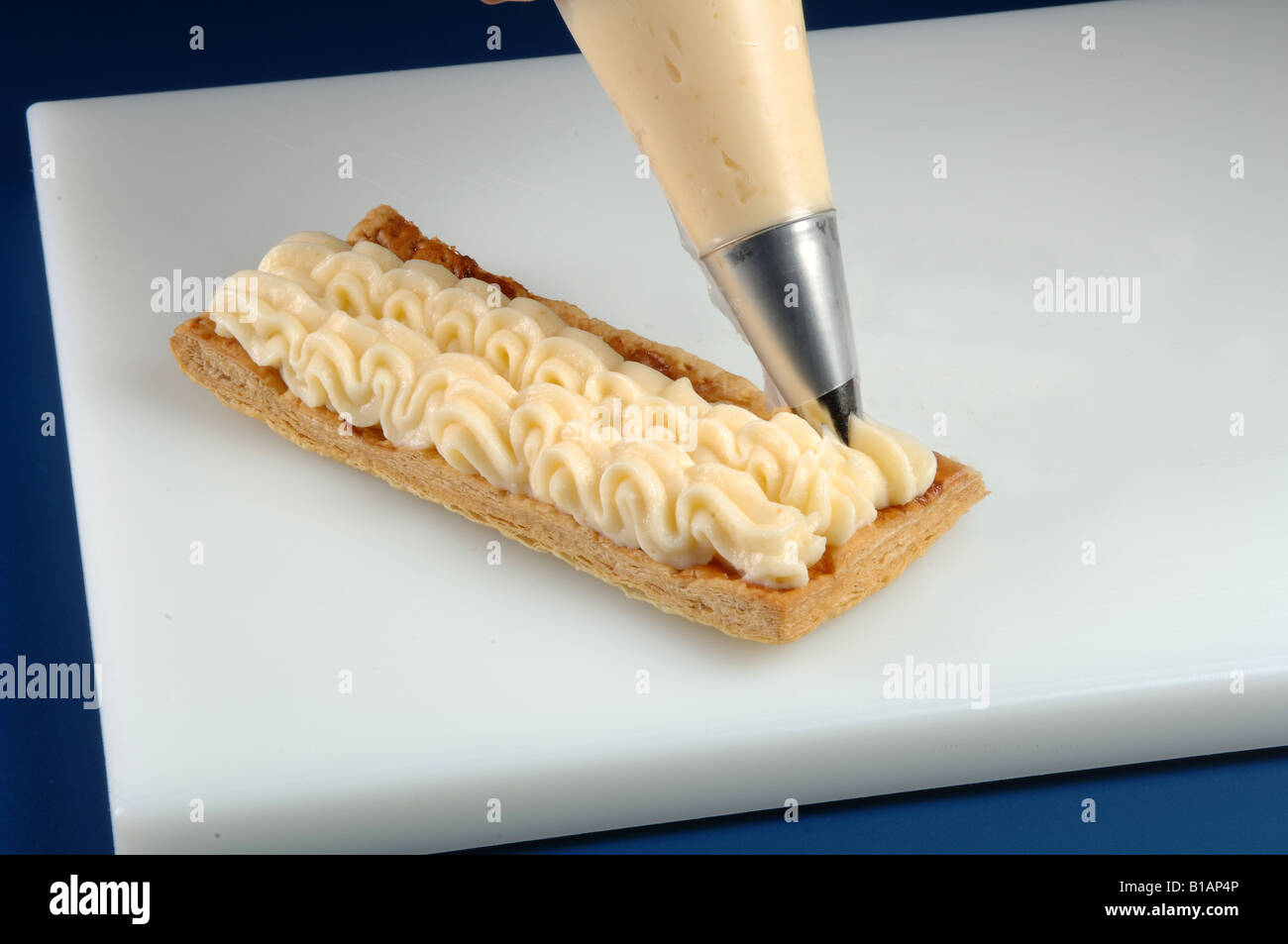 Putting cream on puffy pastry Stock Photo - Alamy