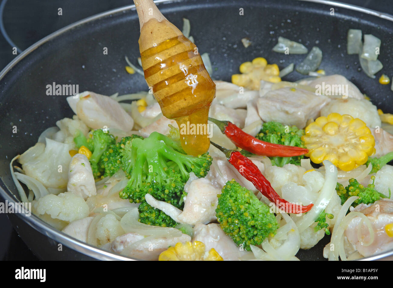 Adding honey to sautéed vegetables Stock Photo - Alamy