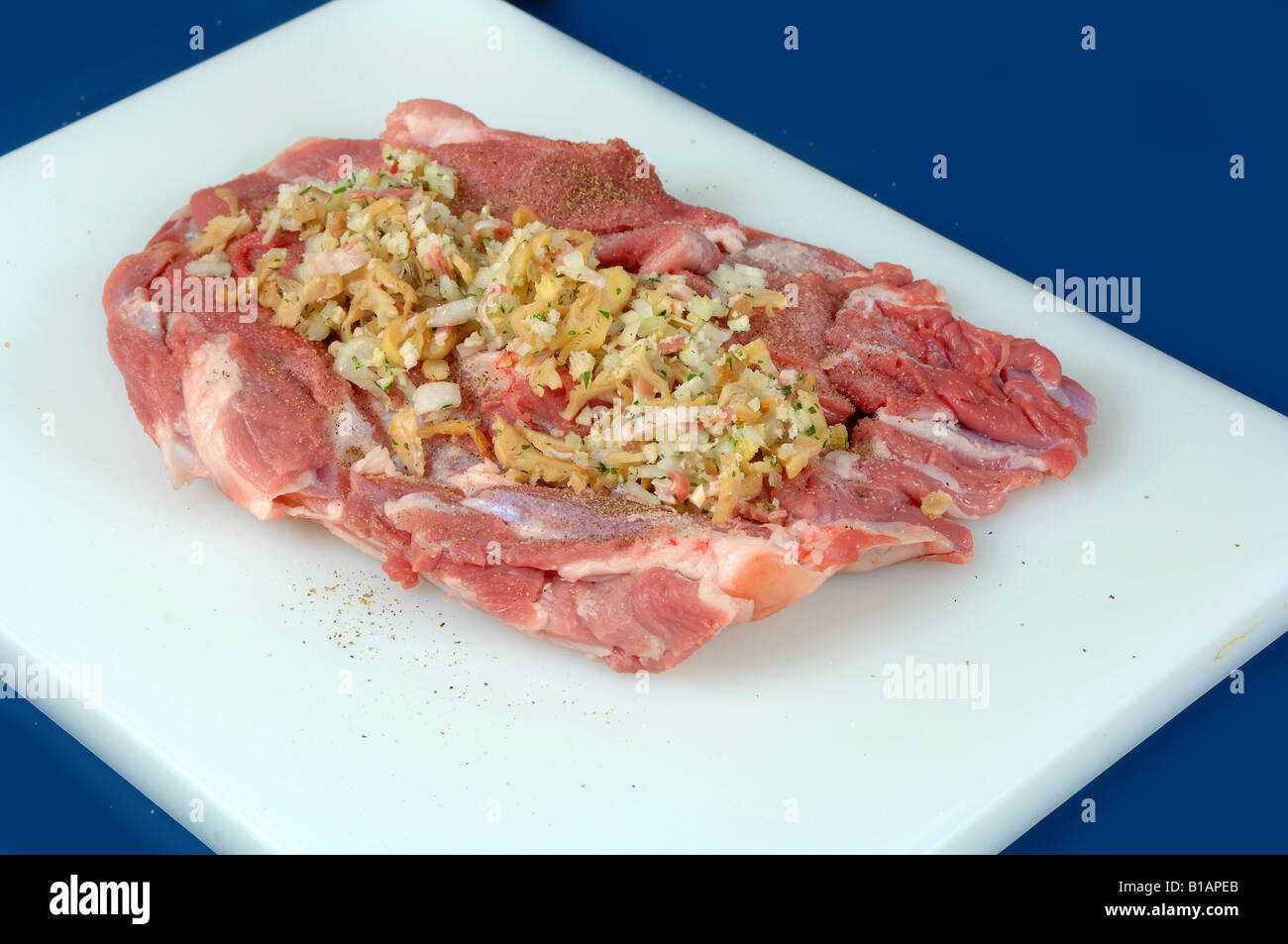 Stuffing sliced and seasoned lamb shoulder Stock Photo - Alamy