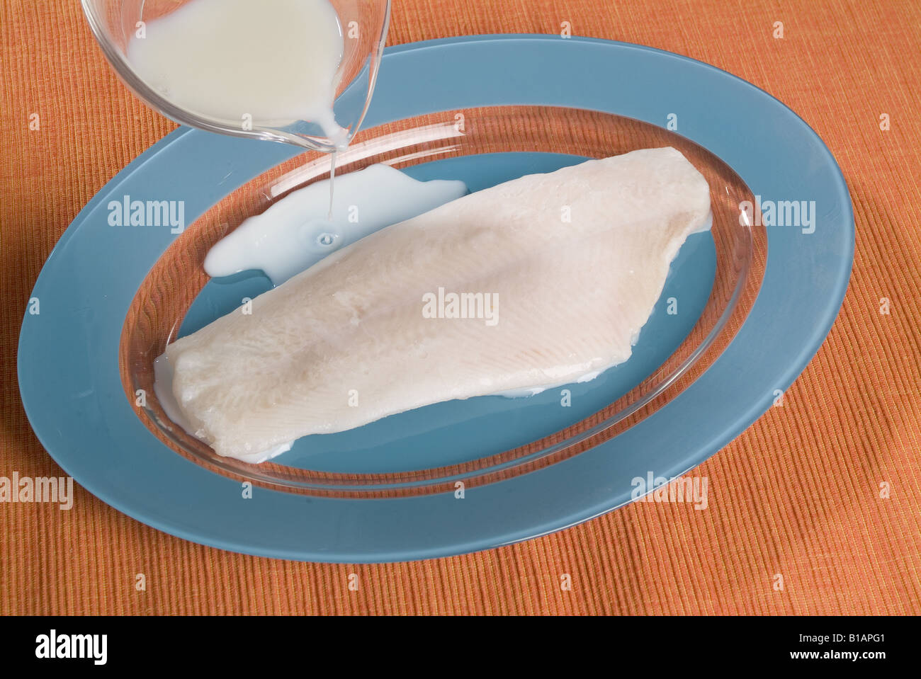 Pouring milk over frozen fish fillet Stock Photo - Alamy