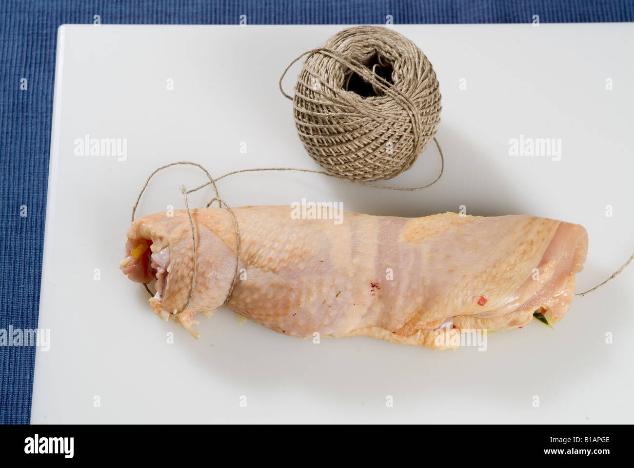 Tying a string around stuffed poussin Stock Photo - Alamy
