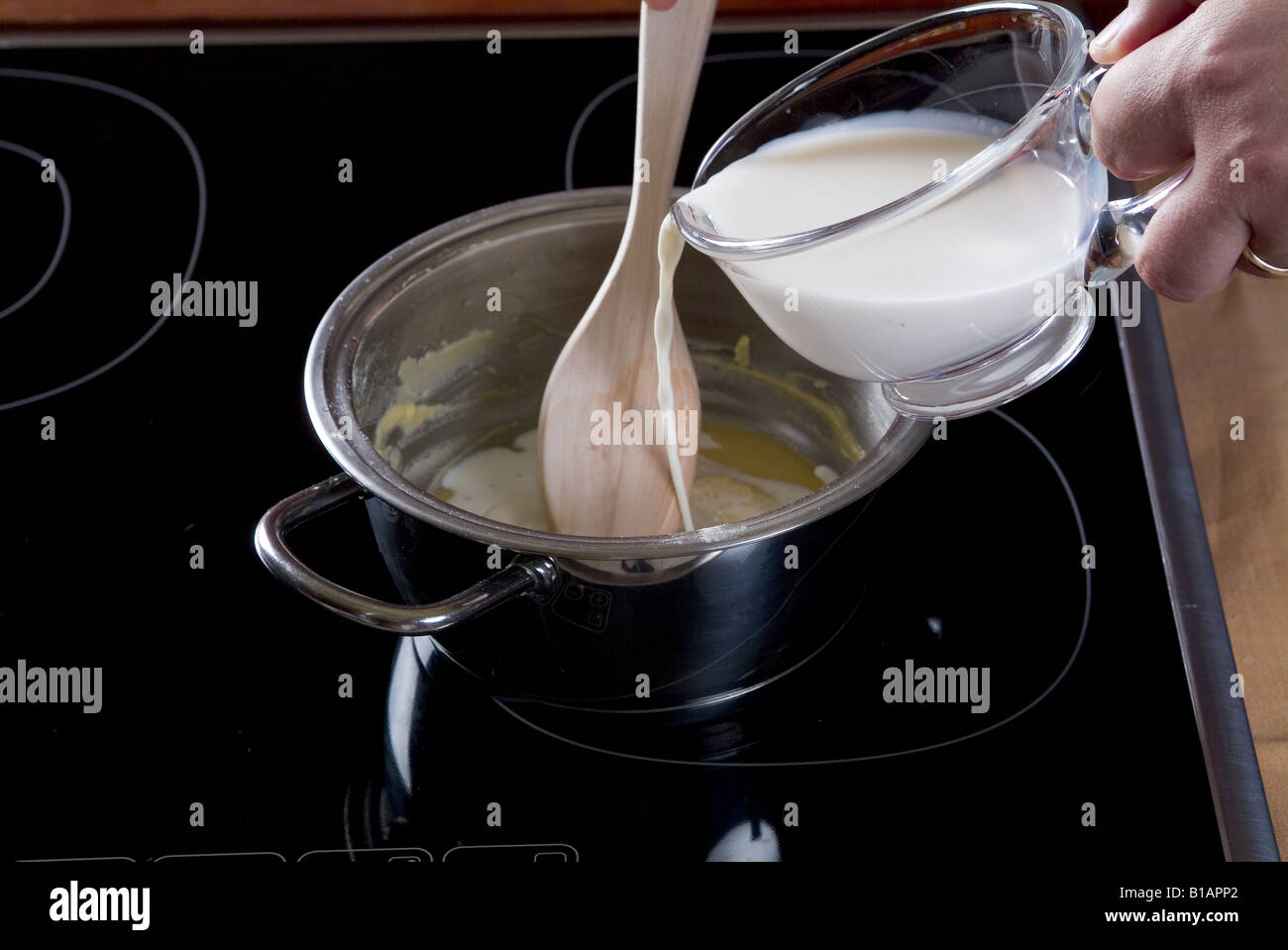 Adding milk while making bechamel sauce Stock Photo - Alamy