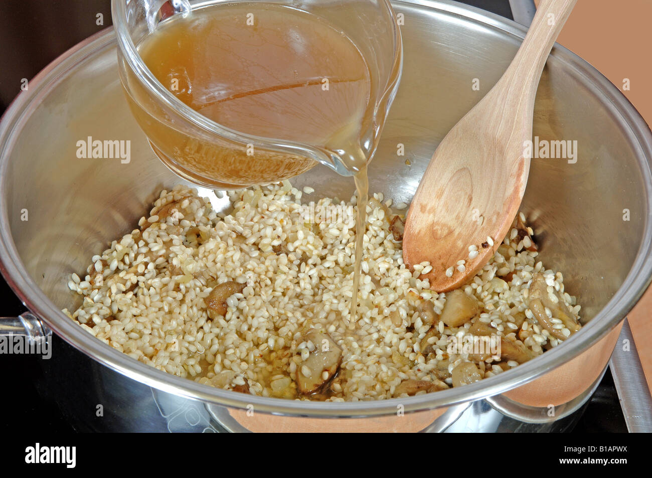 Adding stock to risotto while cooking Stock Photo - Alamy