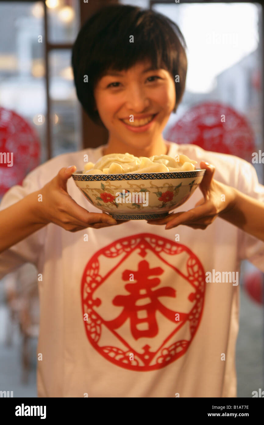 Chinese young woman holding a bowl of Chinese dumpling Stock Photo - Alamy