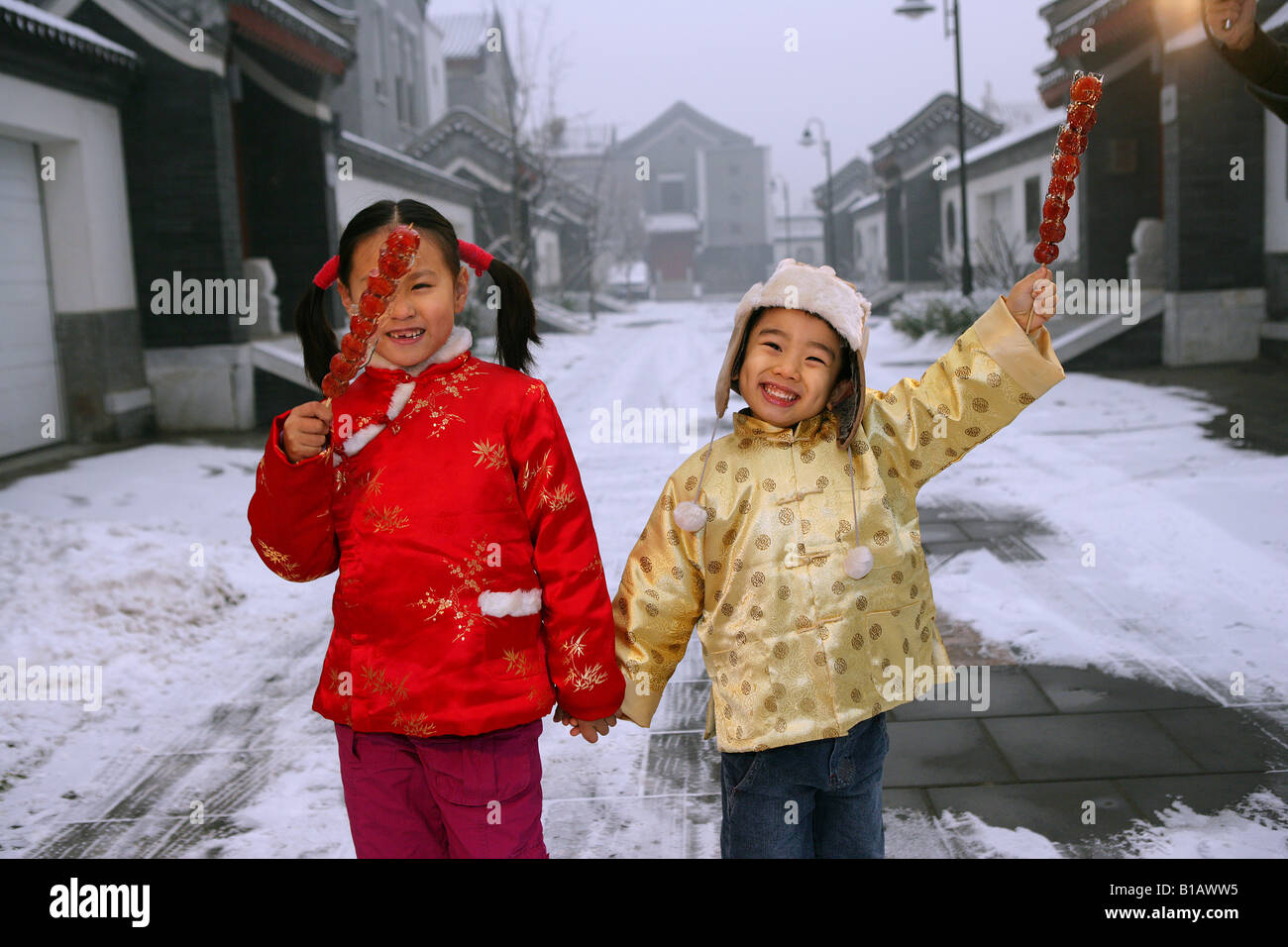 two chinese children dressed in traditional clothing raising candied ...