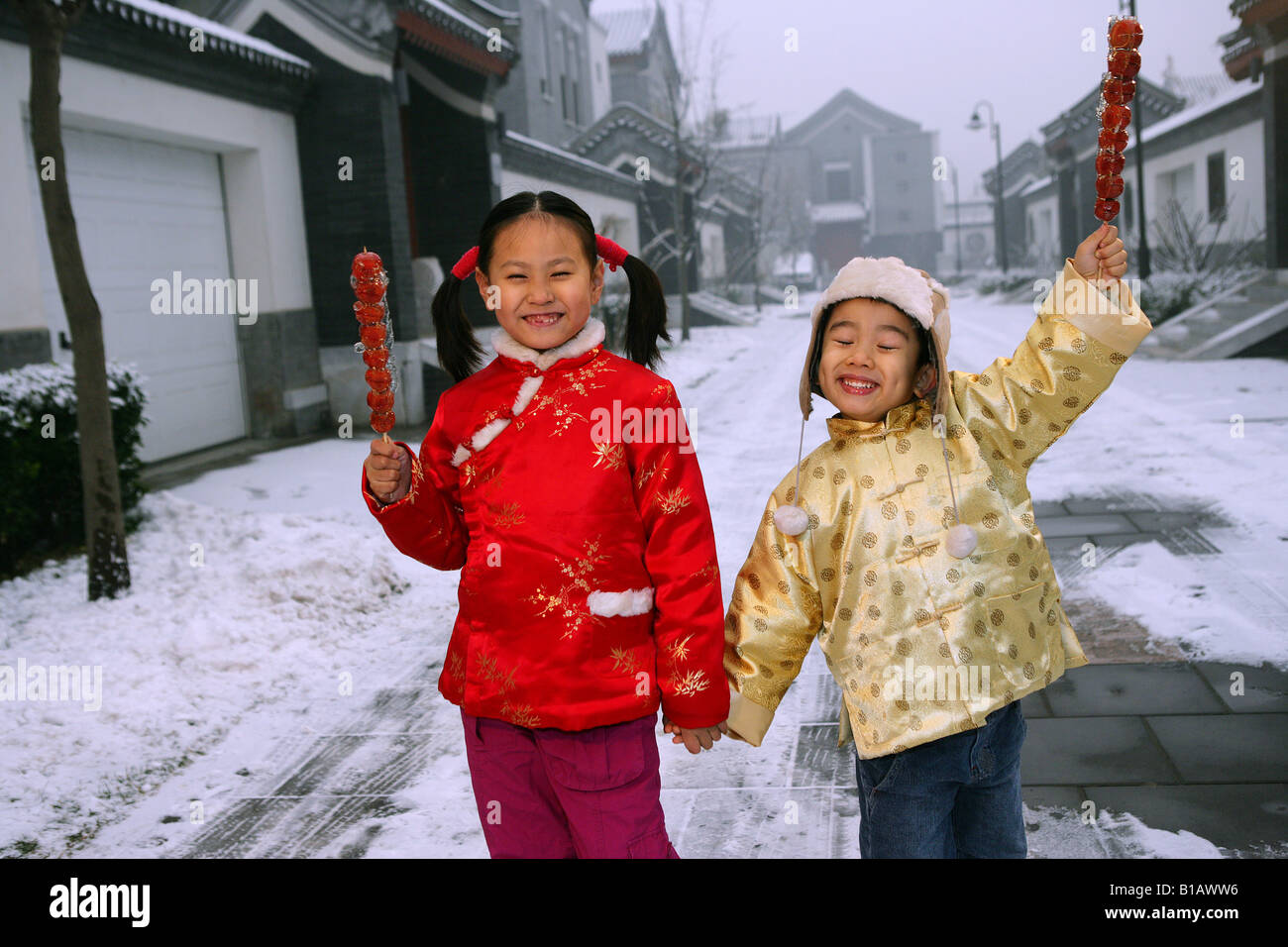 two chinese children dressed in traditional clothing raising candied ...