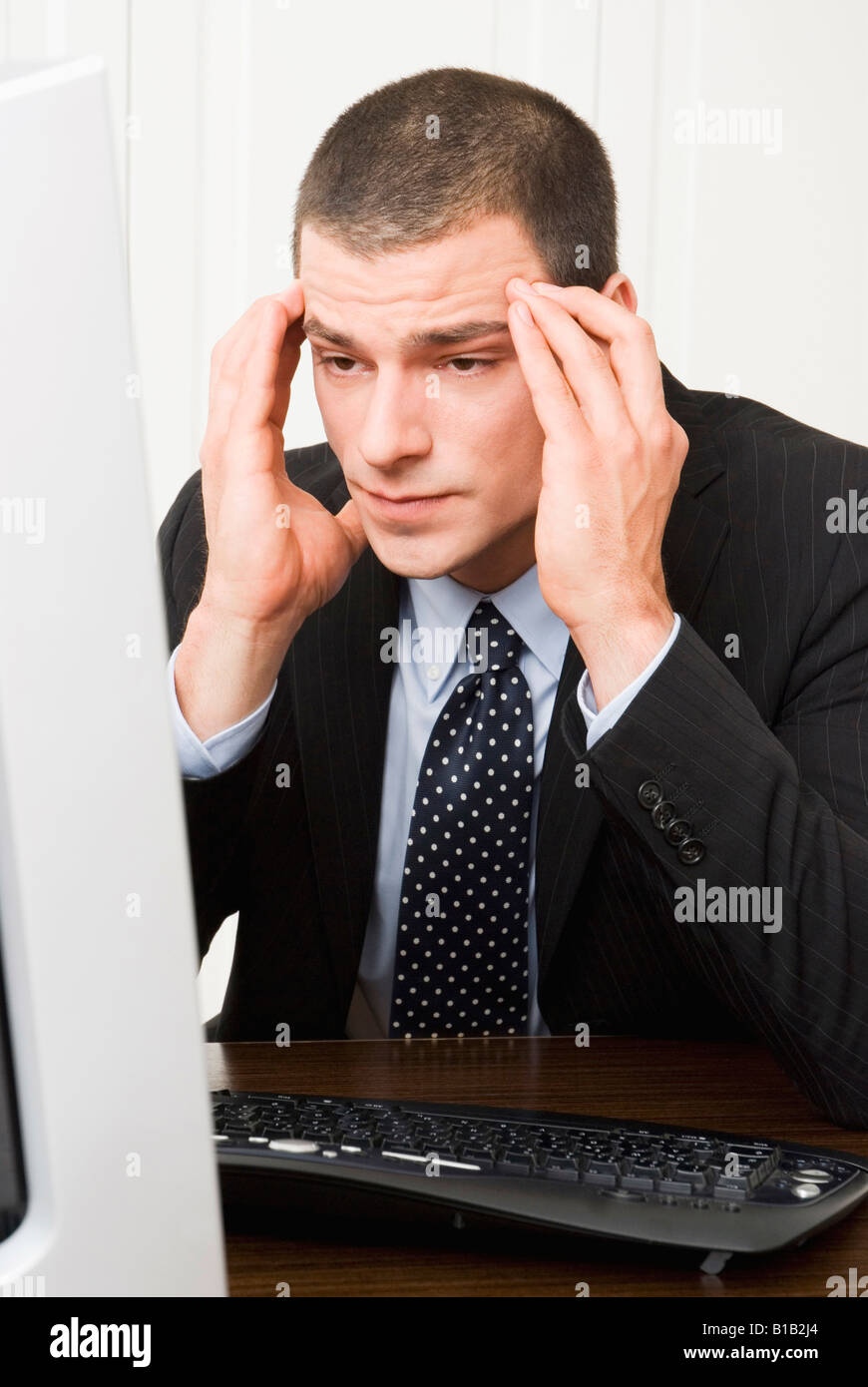 Businessman with hands on forehead looking at pc-screen, close-up ...