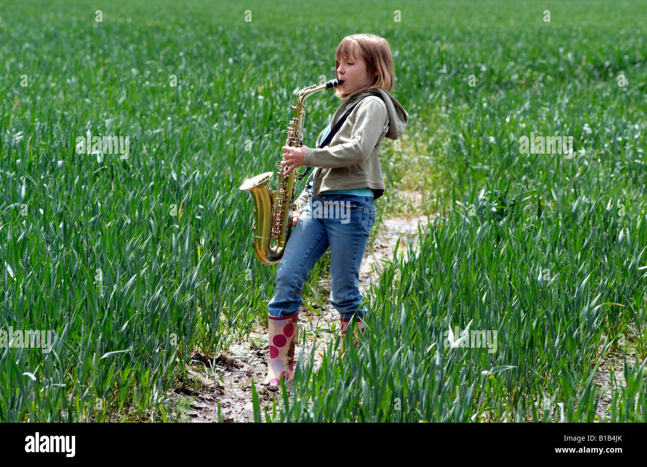 Little girl playing the saxophone in a field of crops Walking through ...