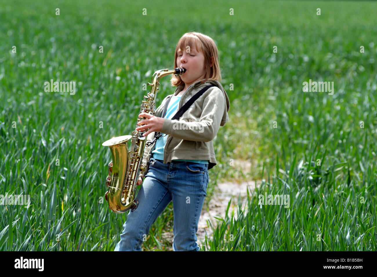Little girl playing the saxophone in a field of crops Walking through ...