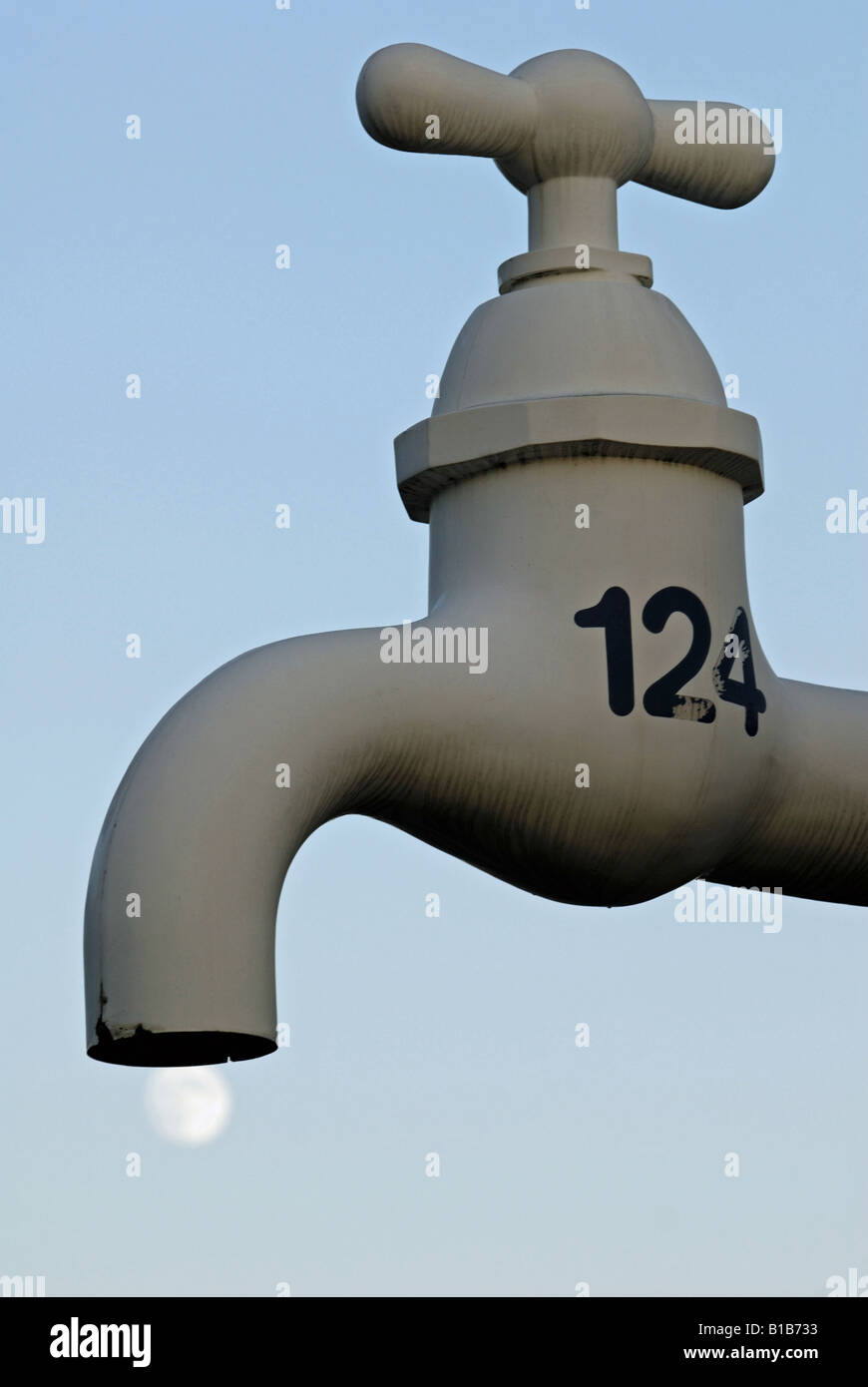 Oversized replica of a water tap with the full moon rising up the spout ...