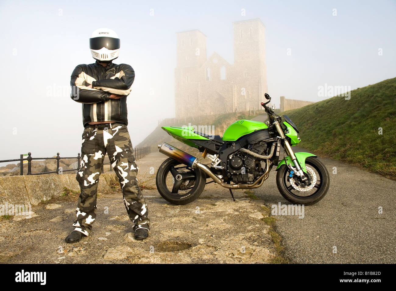 biker posing by his green motorcycle misty afternoon by castle Stock ...