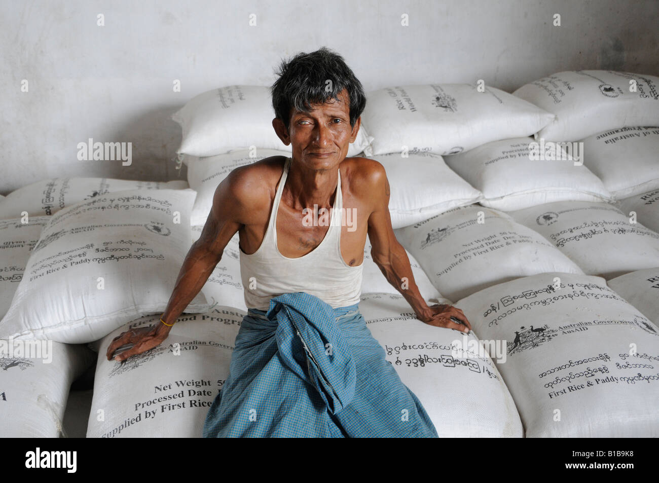 A worker sits over sacks of rice donated by United Nations World Food ...