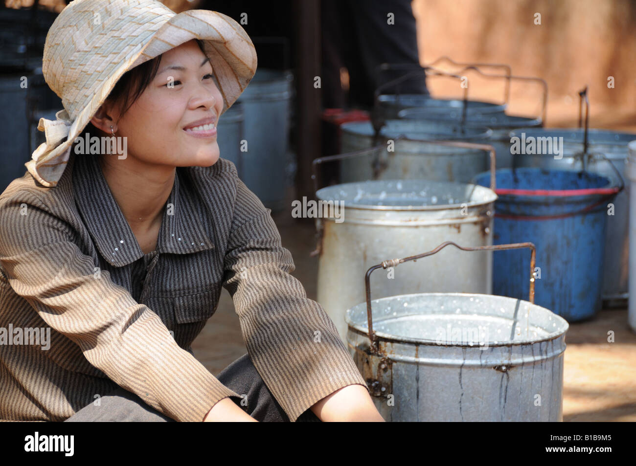 Vietnamese woman resting after collecting rubber at a plantation ...