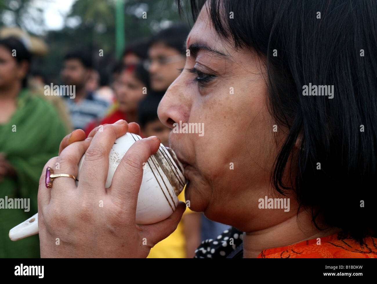 A Bengali woman blows a conch shell as a form of worship celebrating ...