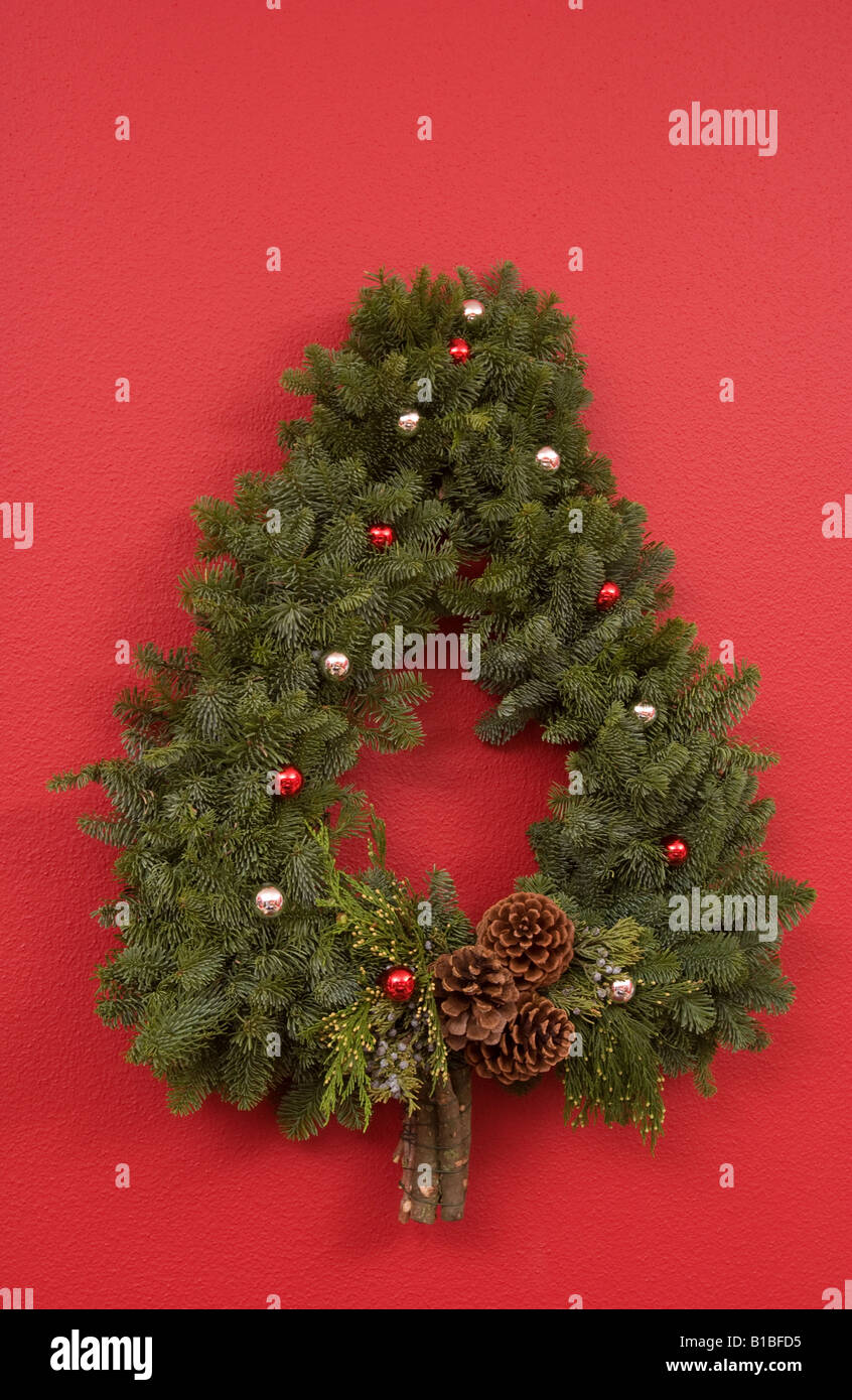 Christmas tree shaped wreath on red wall Stock Photo - Alamy