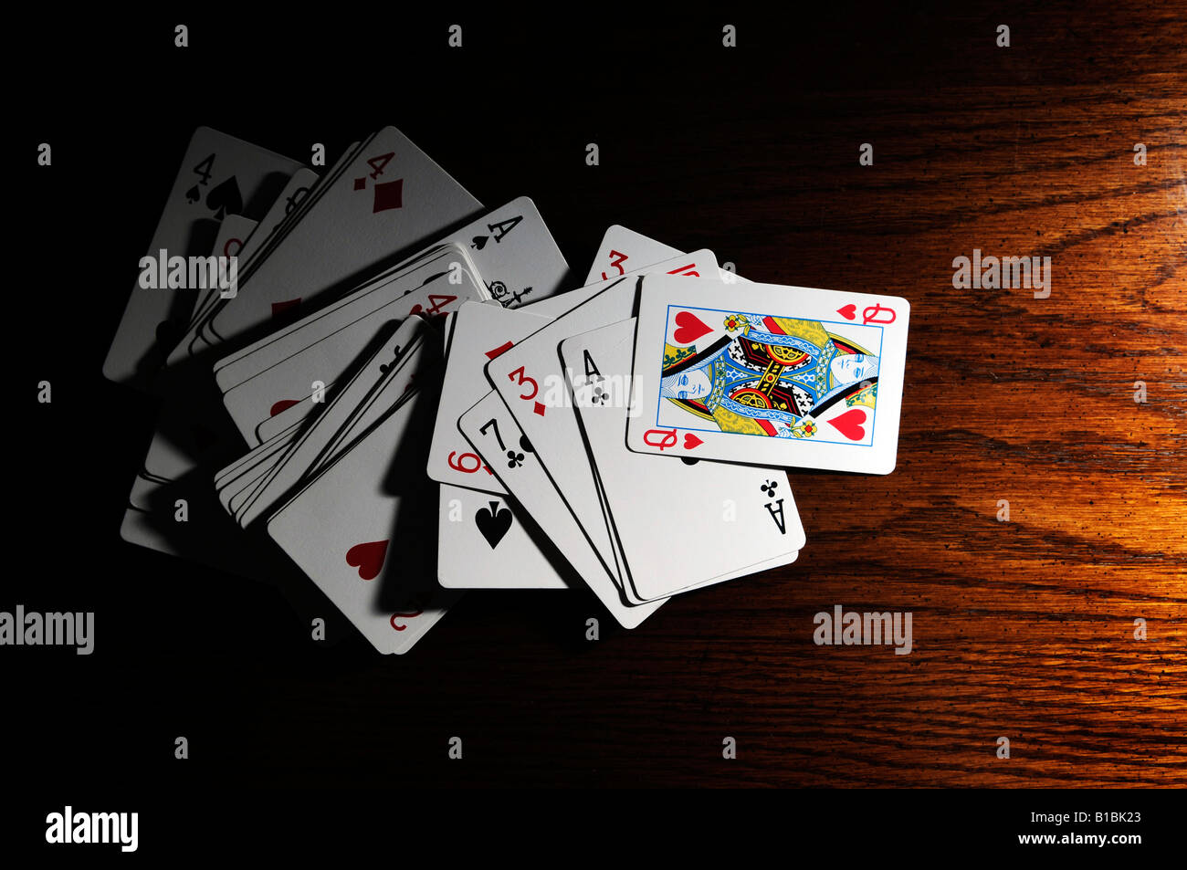 playing cards scattered across wood table Stock Photo - Alamy