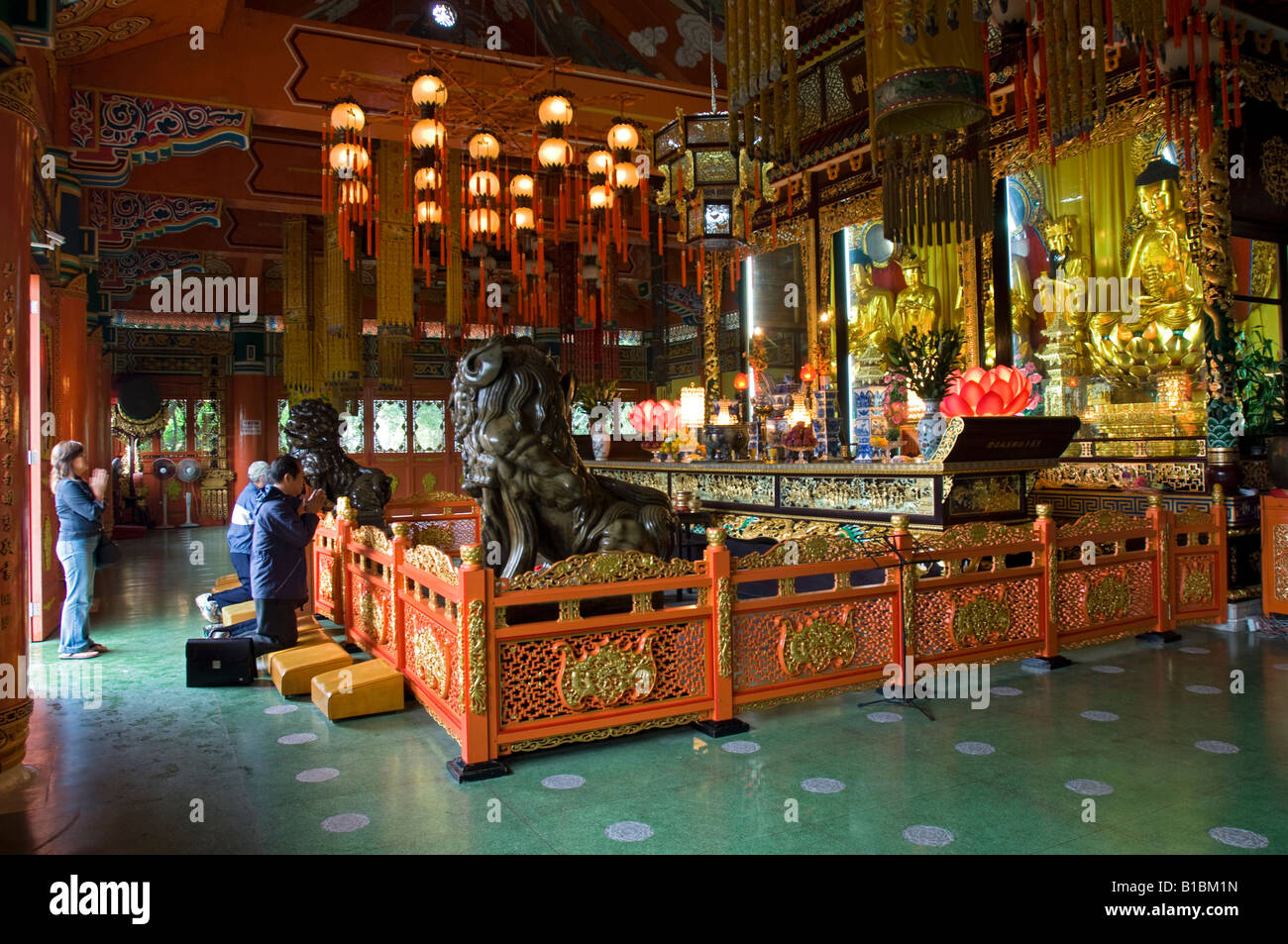 Inside the Hall of the Great Hero at Po Lin Monastery. Pilgrims praying ...