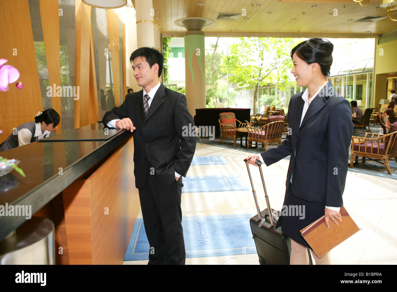 businessman and businesswoman standing at hotel reception Stock Photo ...