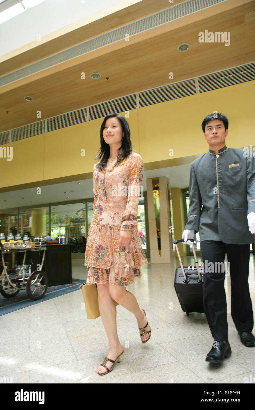 young woman and bellhop walking at hotel hall Stock Photo - Alamy