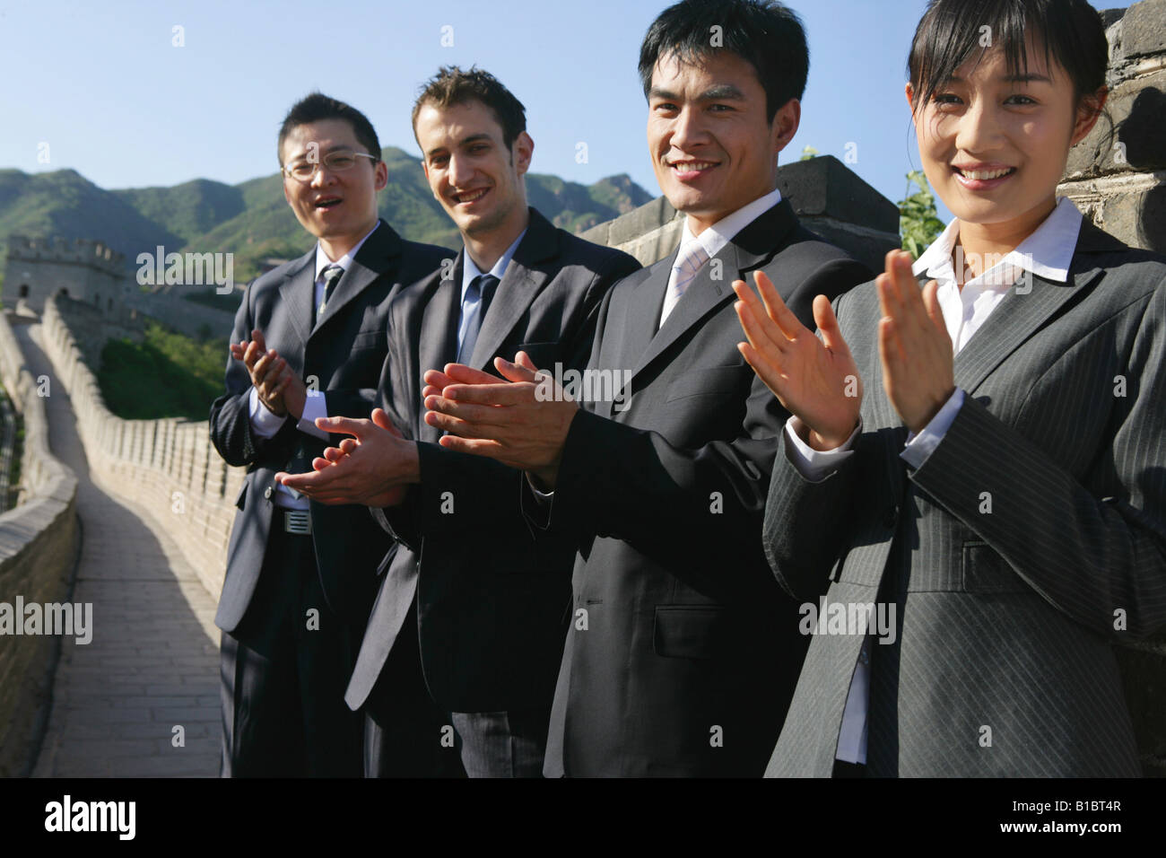 three businessmen and one businesswoman clapping on Great Wall,Beijing ...