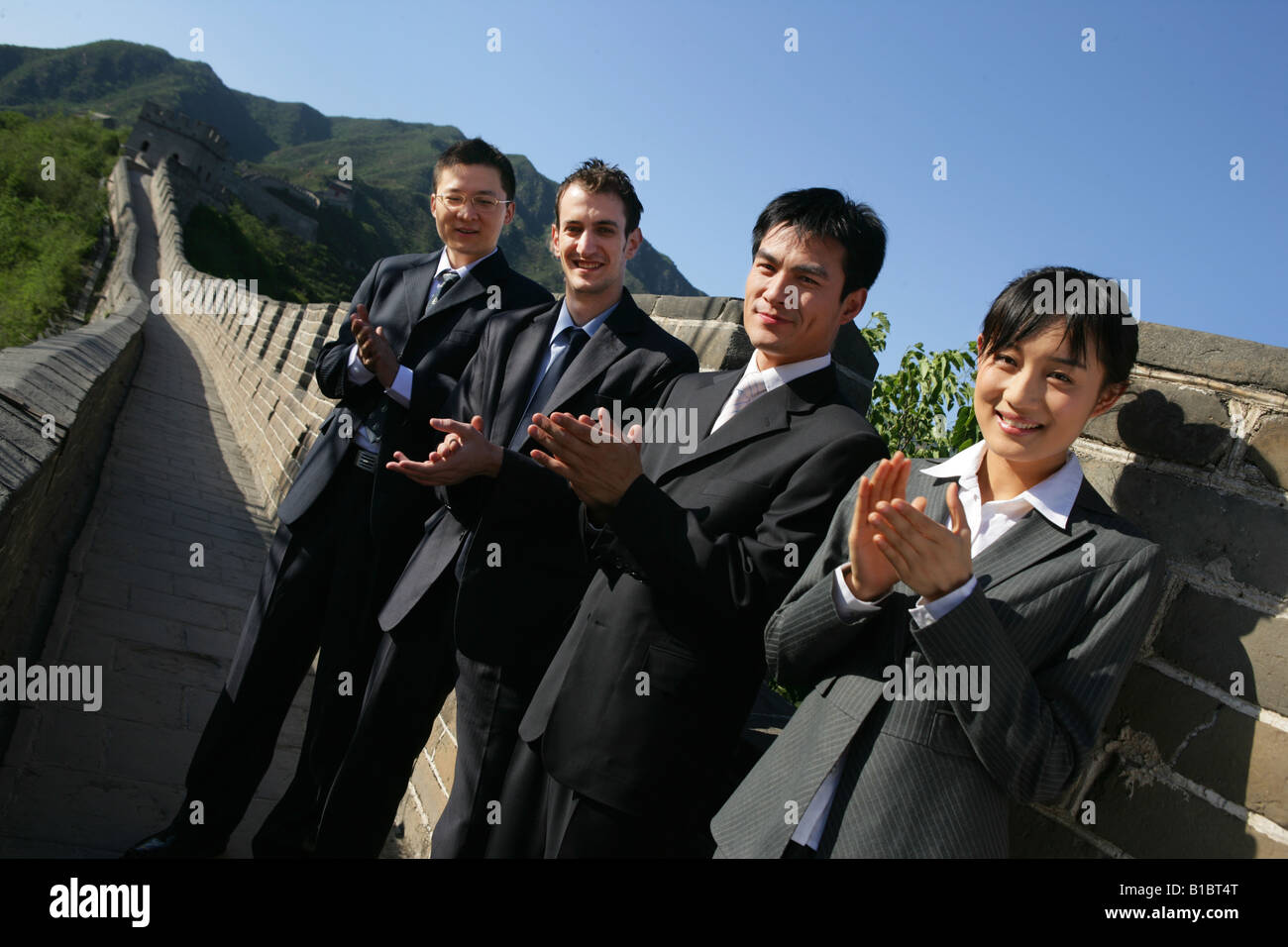 three businessmen and one businesswoman clapping on Great Wall,Beijing ...