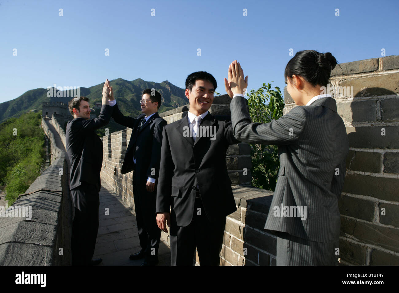 three businessmen and one businesswoman clapping on Great Wall,Beijing ...