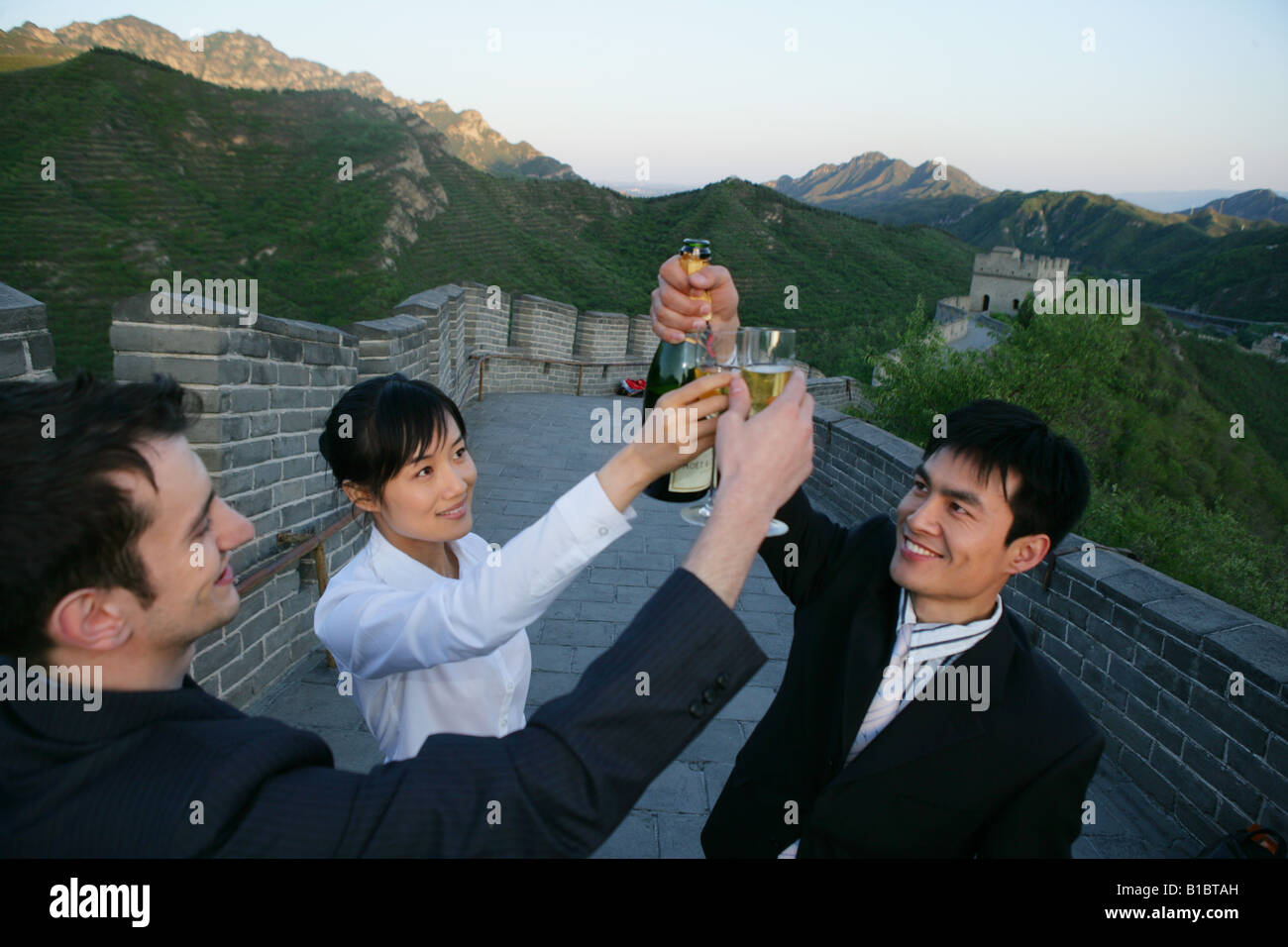 two businessmen and one businesswoman toasting on Great Wall,Beijing ...