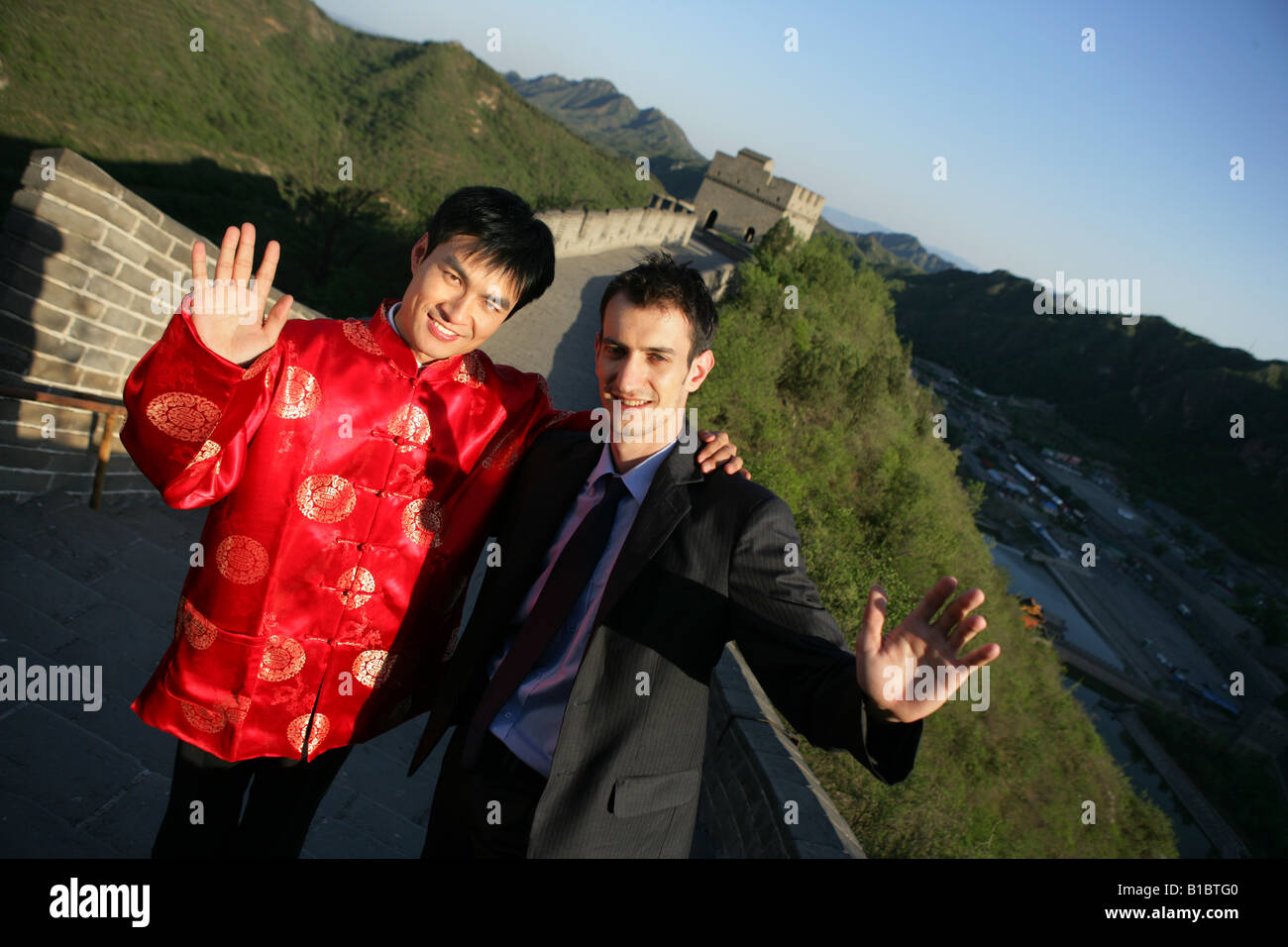 Chinese traditional man and caucasian businessman waving on Great Wall ...
