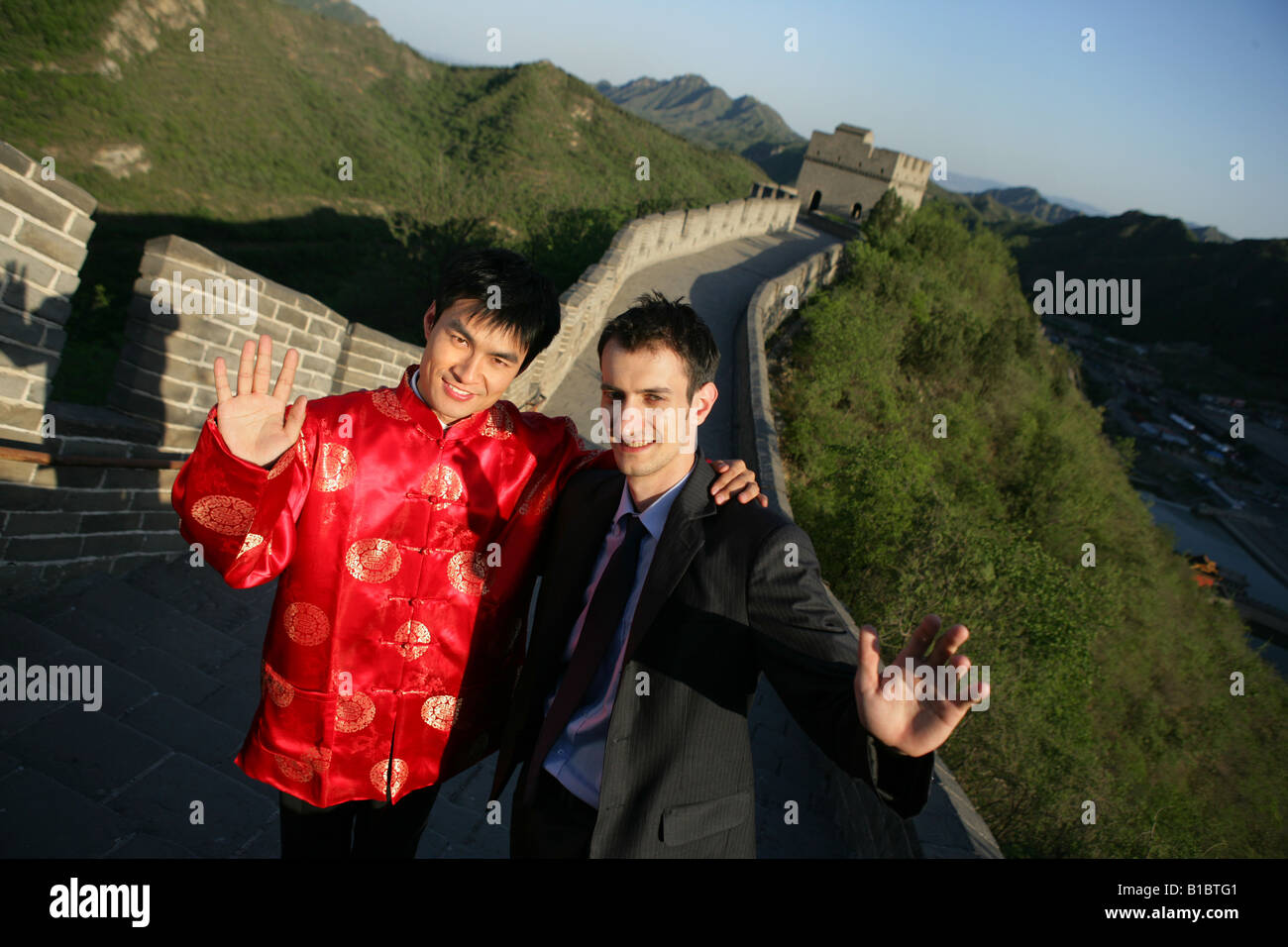 Chinese traditional man and caucasian businessman waving on Great Wall ...